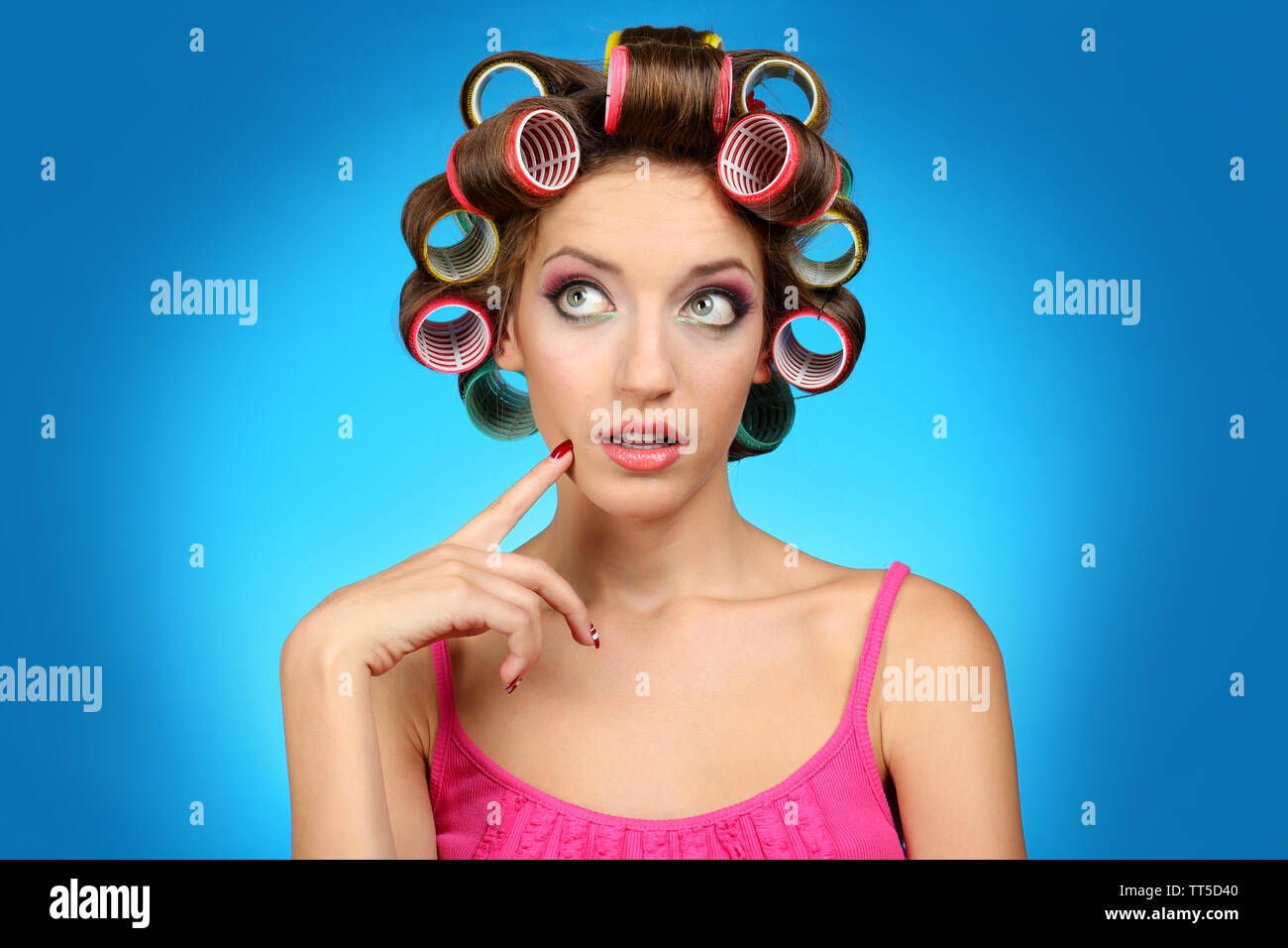 Beautiful girl in hair curlers on blue background Stock Photo - Alamy
