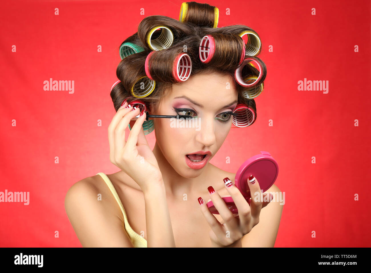 Beautiful girl in hair curlers on red background Stock Photo - Alamy