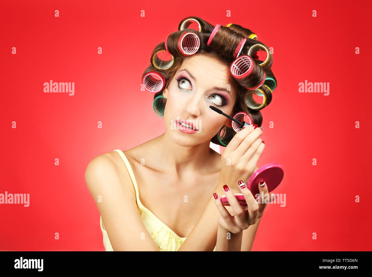 Beautiful girl in hair curlers on red background Stock Photo - Alamy