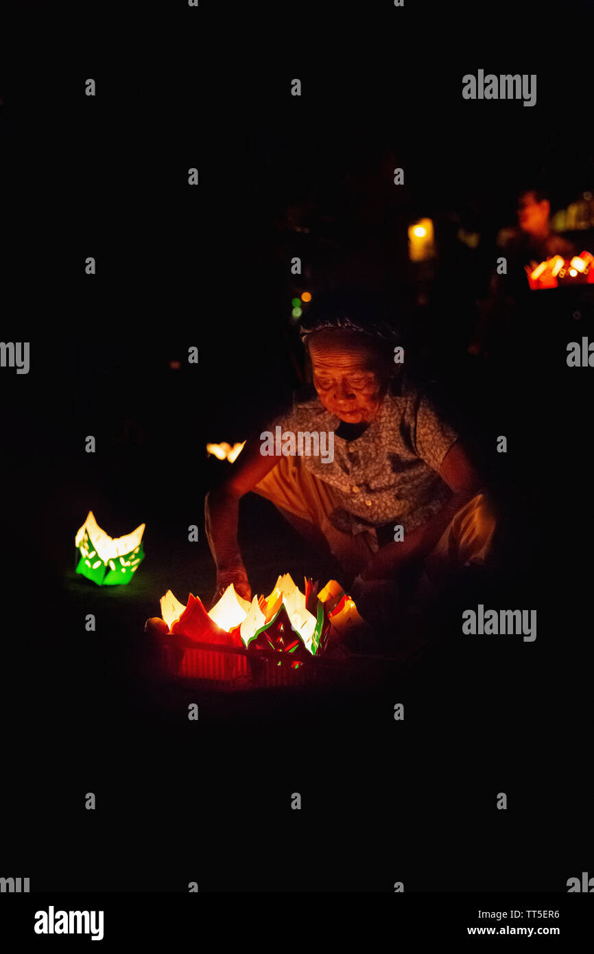 Vietnamese woman lighting a paper lantern at night, Hoi An, Quang Nam ...