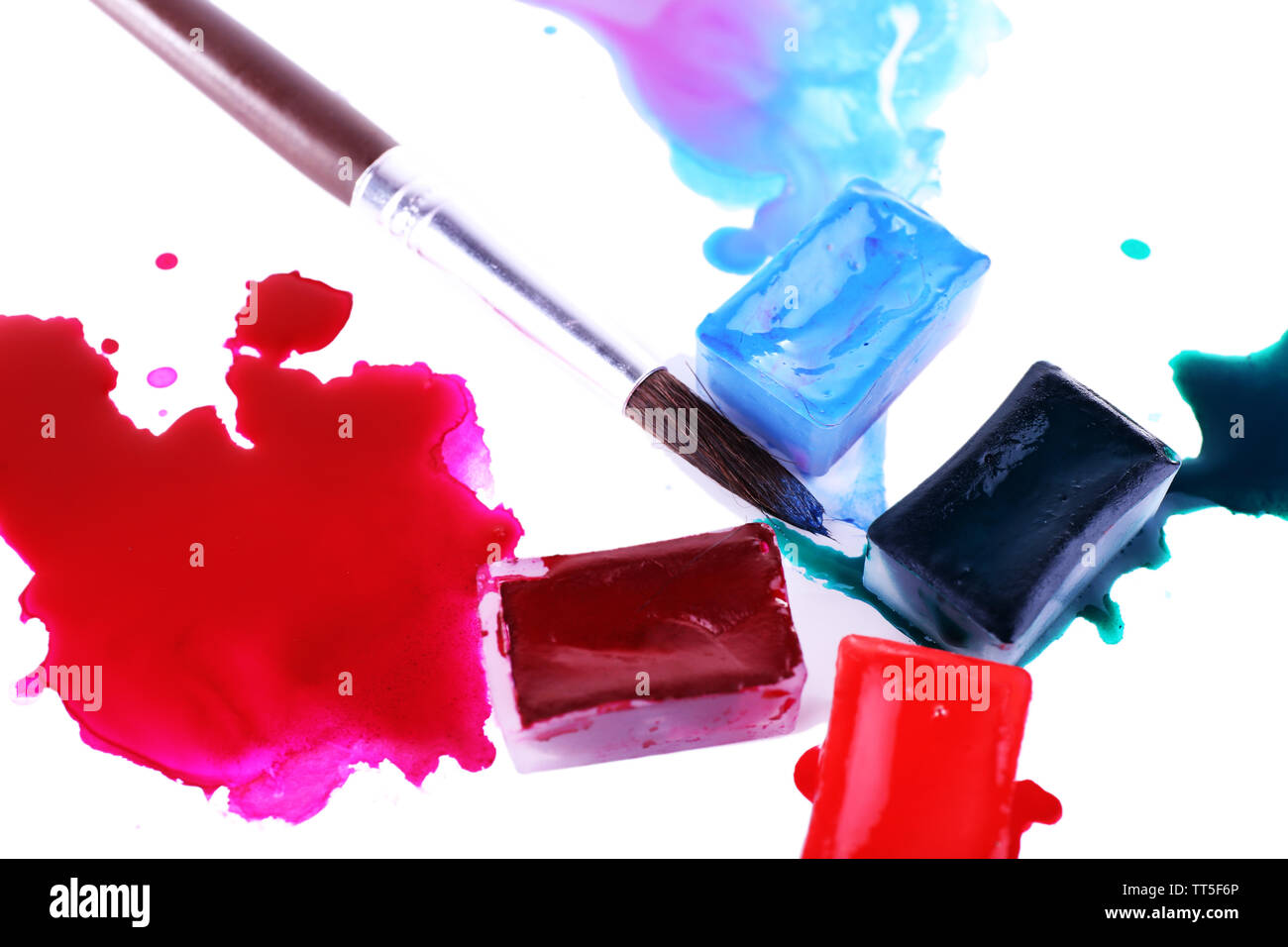 Watercolor paint cubes with brush and spilled paint isolated on white ...