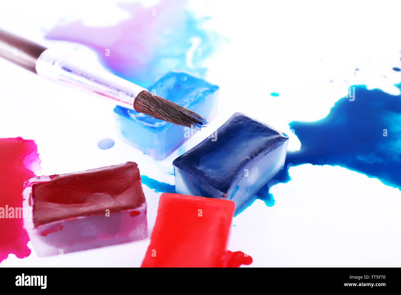 Watercolor paint cubes with brush and spilled paint isolated on white ...