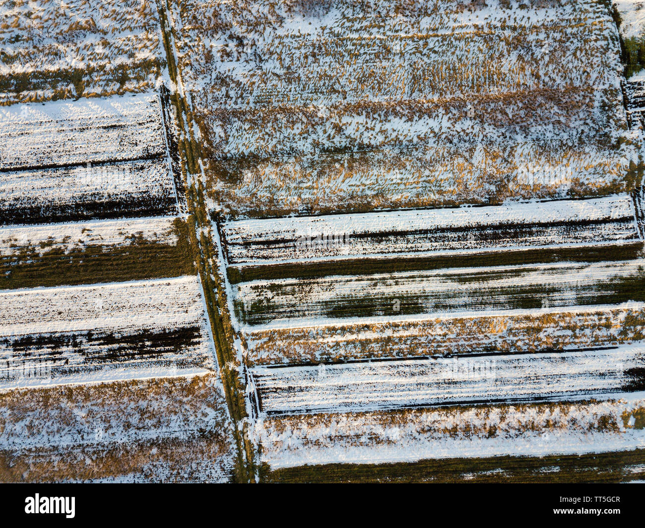 Top view of empty snowy and dark fields patched landscape on sunny ...