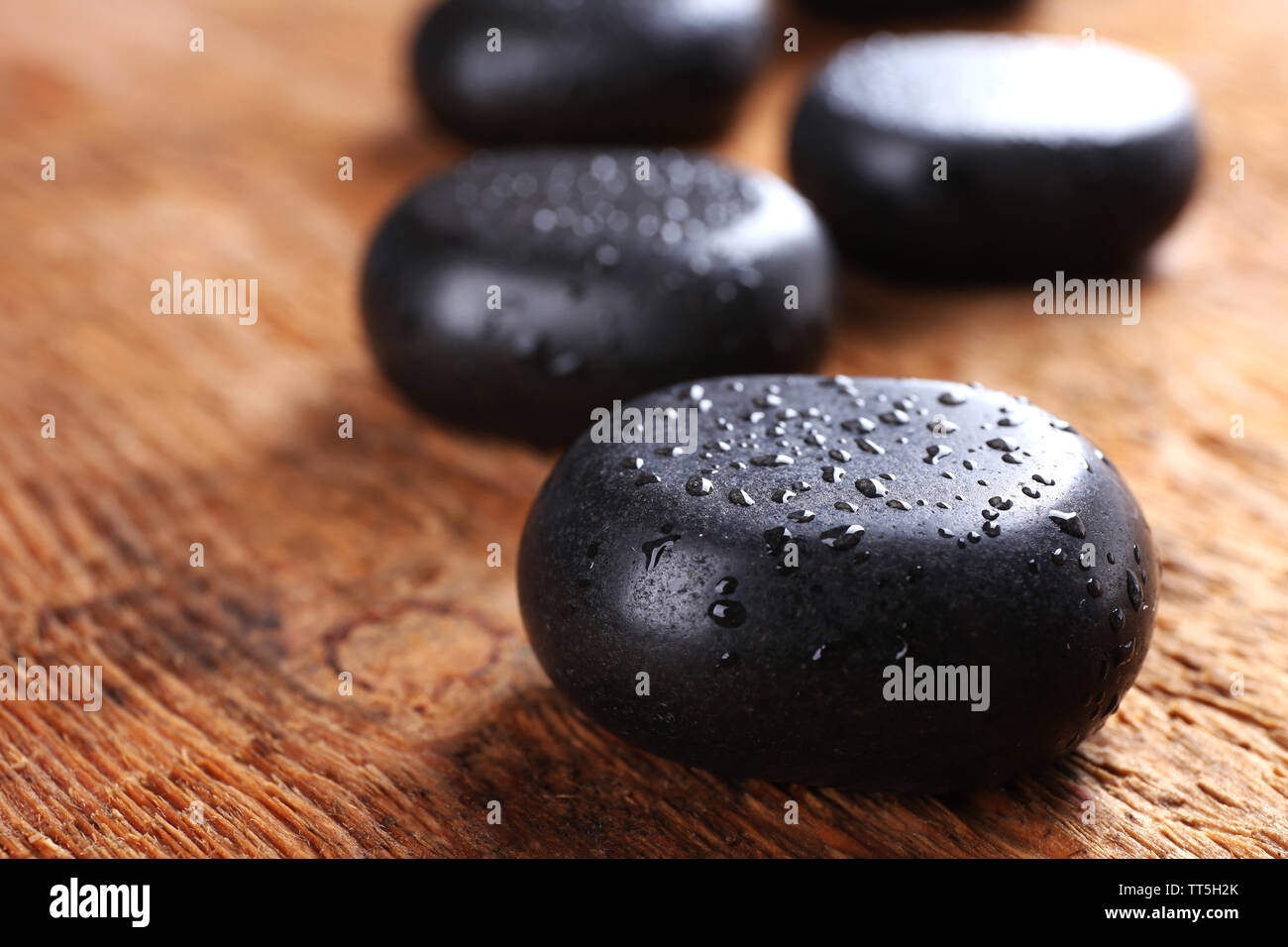 Spa stones with drops on wooden background Stock Photo - Alamy