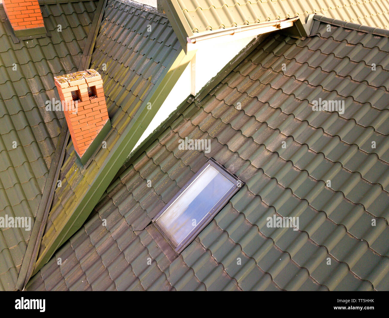 Close-up of new attic plastic window installed in shingled house roof ...