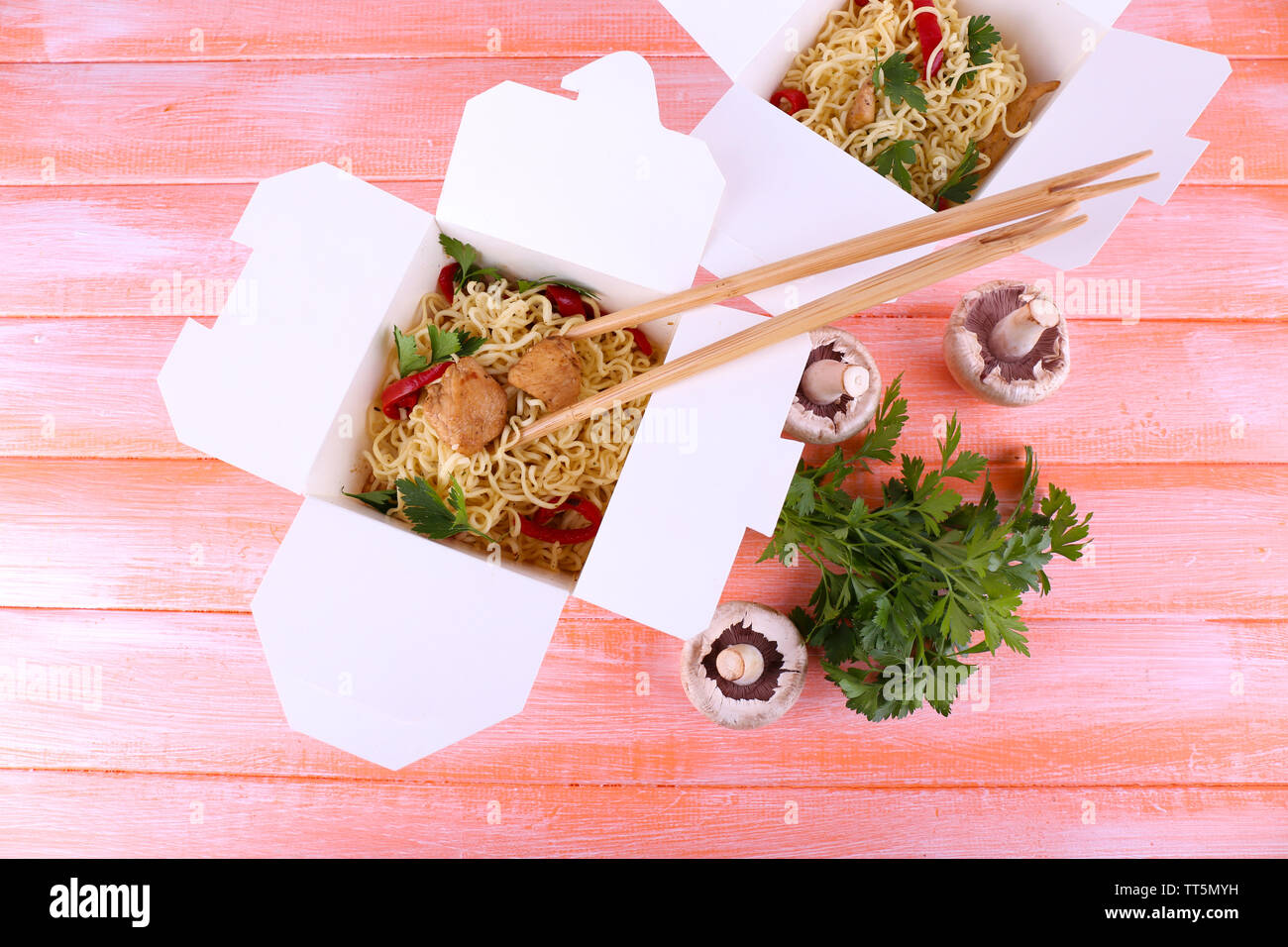 Chinese noodles with meat and pepper in takeaway boxes on pink ...
