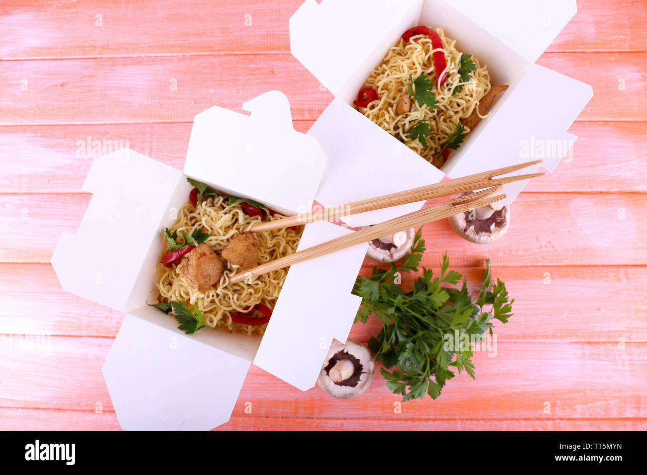 Chinese noodles with meat and pepper in takeaway boxes on pink ...