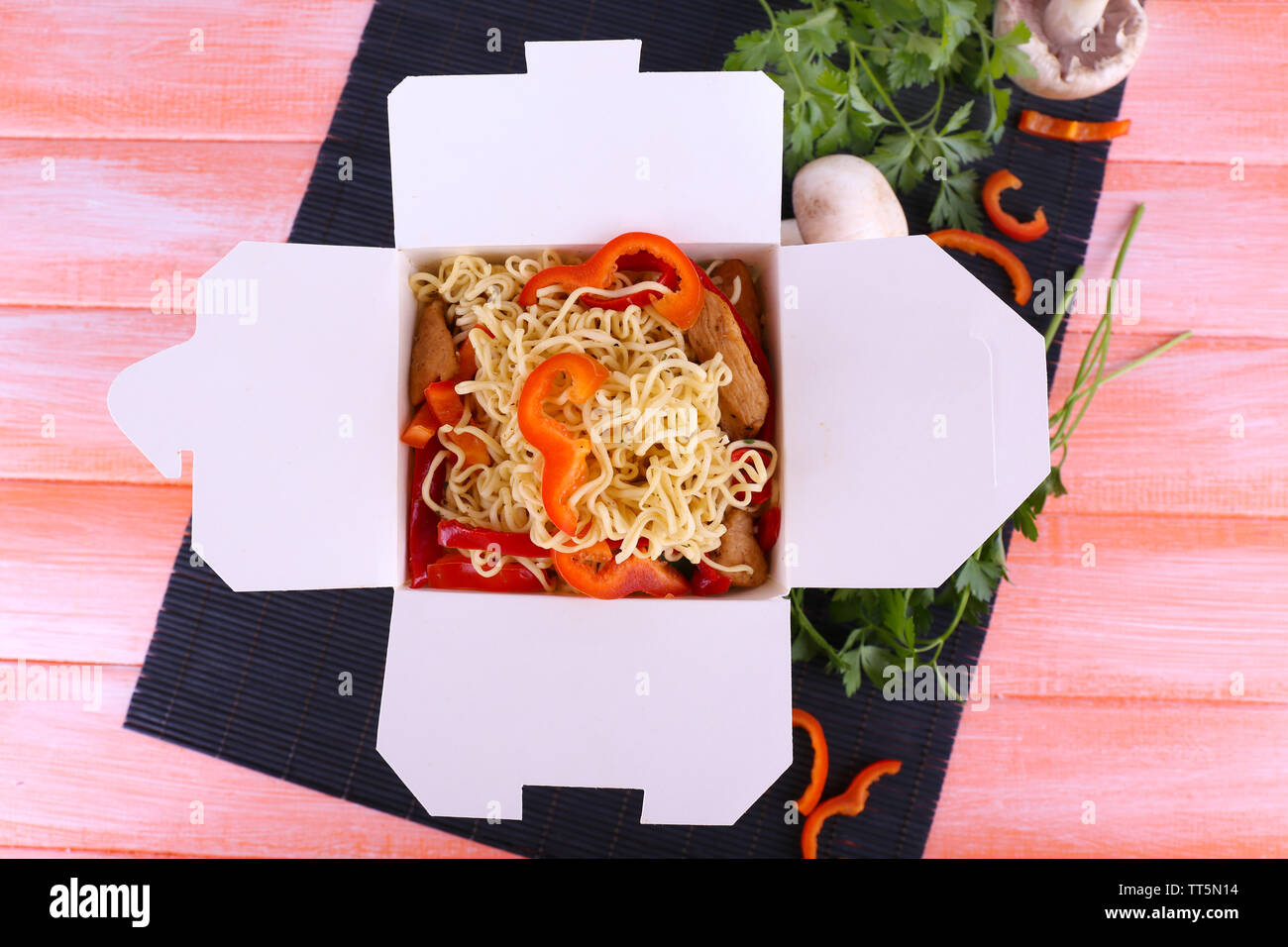Chinese noodles in takeaway box on black mat on pink background Stock ...