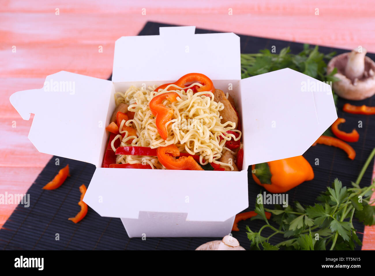 Chinese noodles in takeaway box on black mat on pink background Stock ...