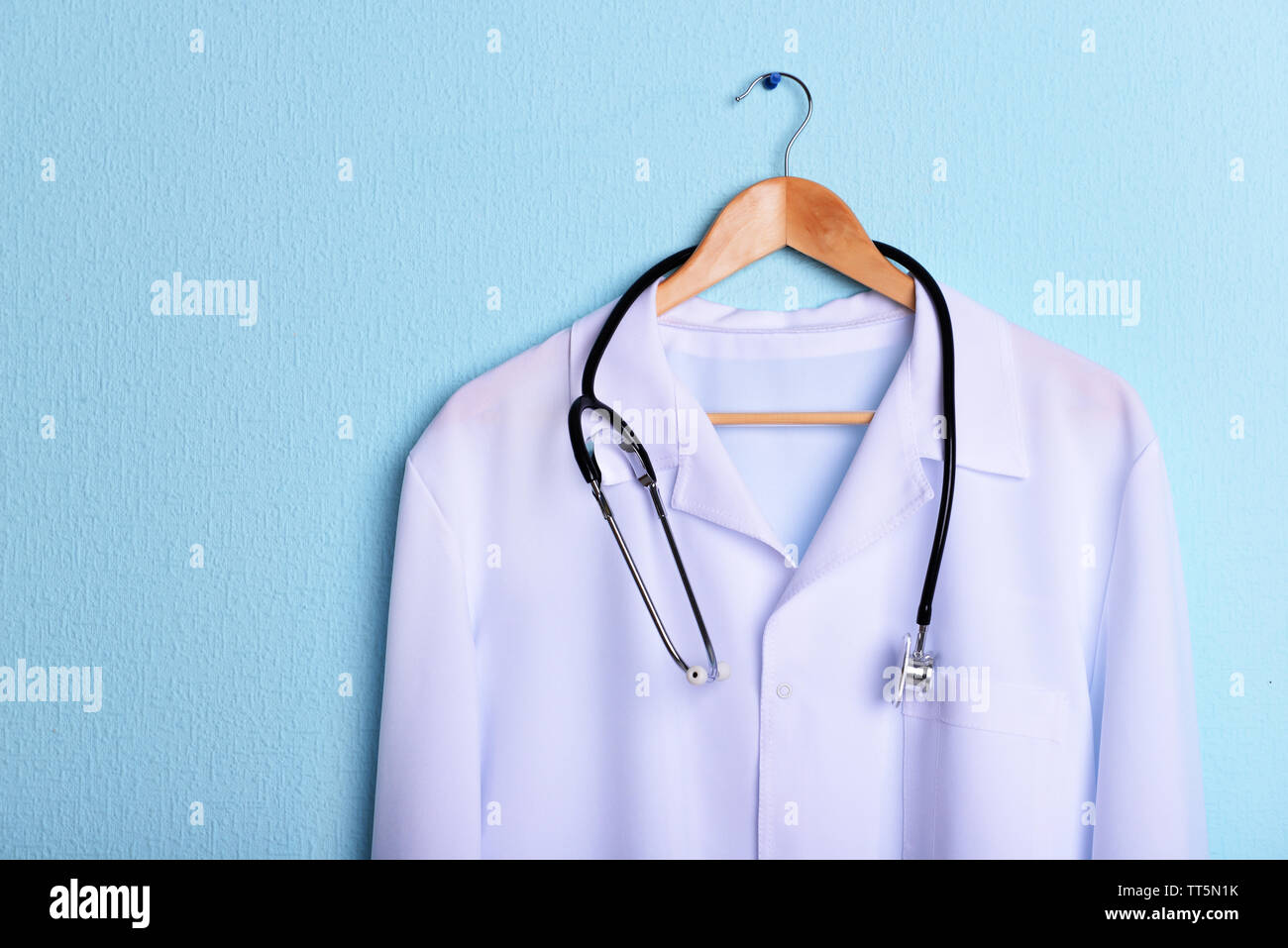 Doctor coat with stethoscope on hanger on blue background Stock Photo ...