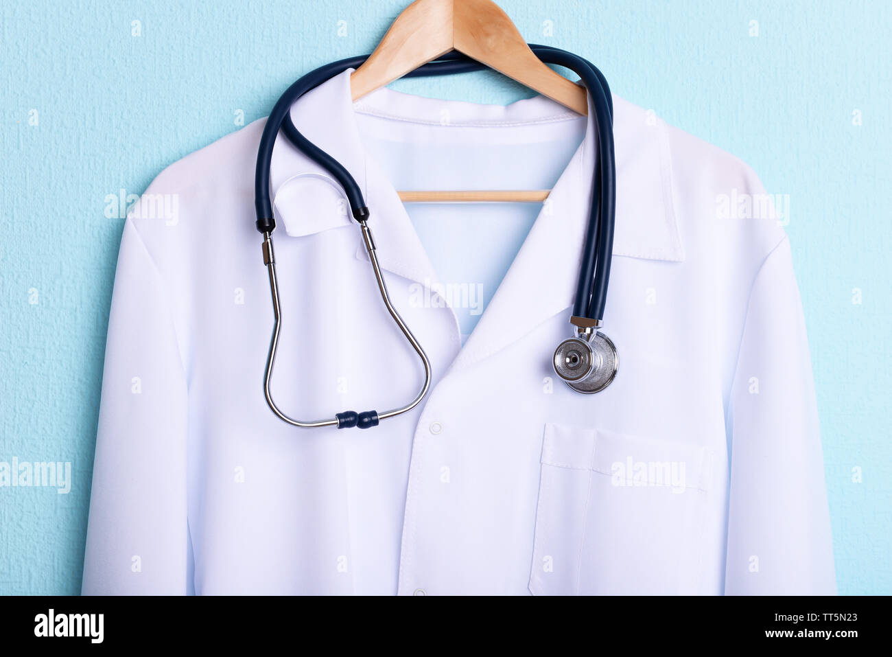 Doctor coat with stethoscope on hanger on blue background Stock Photo ...