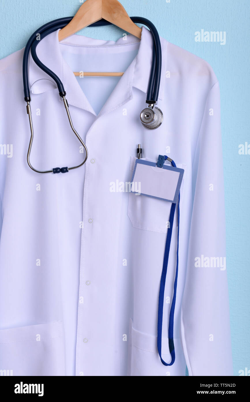 Doctor coat with stethoscope on hanger on blue background Stock Photo ...