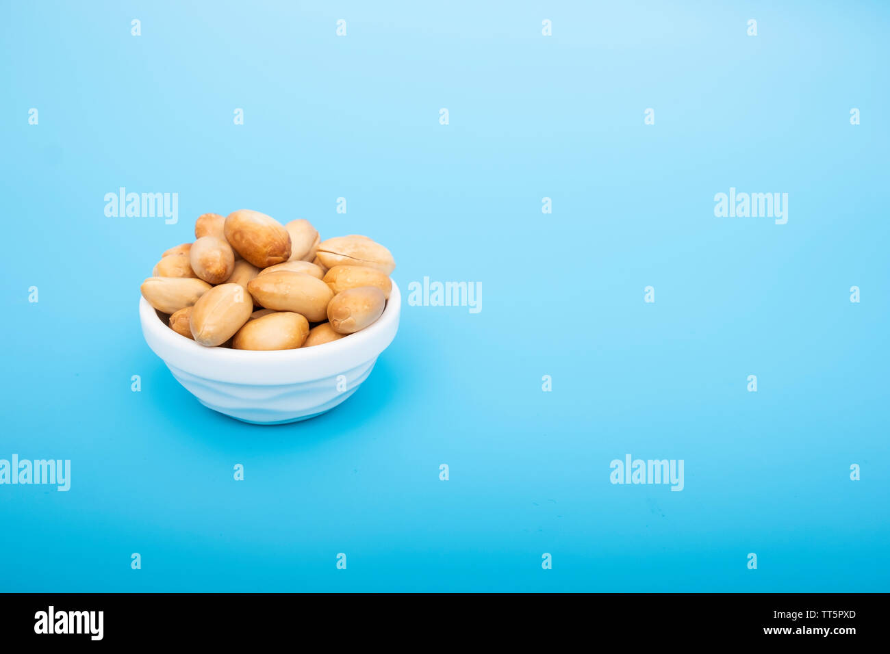 Roasted peanuts isolated on blue surface Stock Photo - Alamy