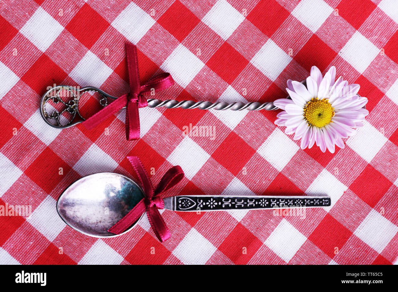 Metal spoons on checkered fabric background Stock Photo - Alamy