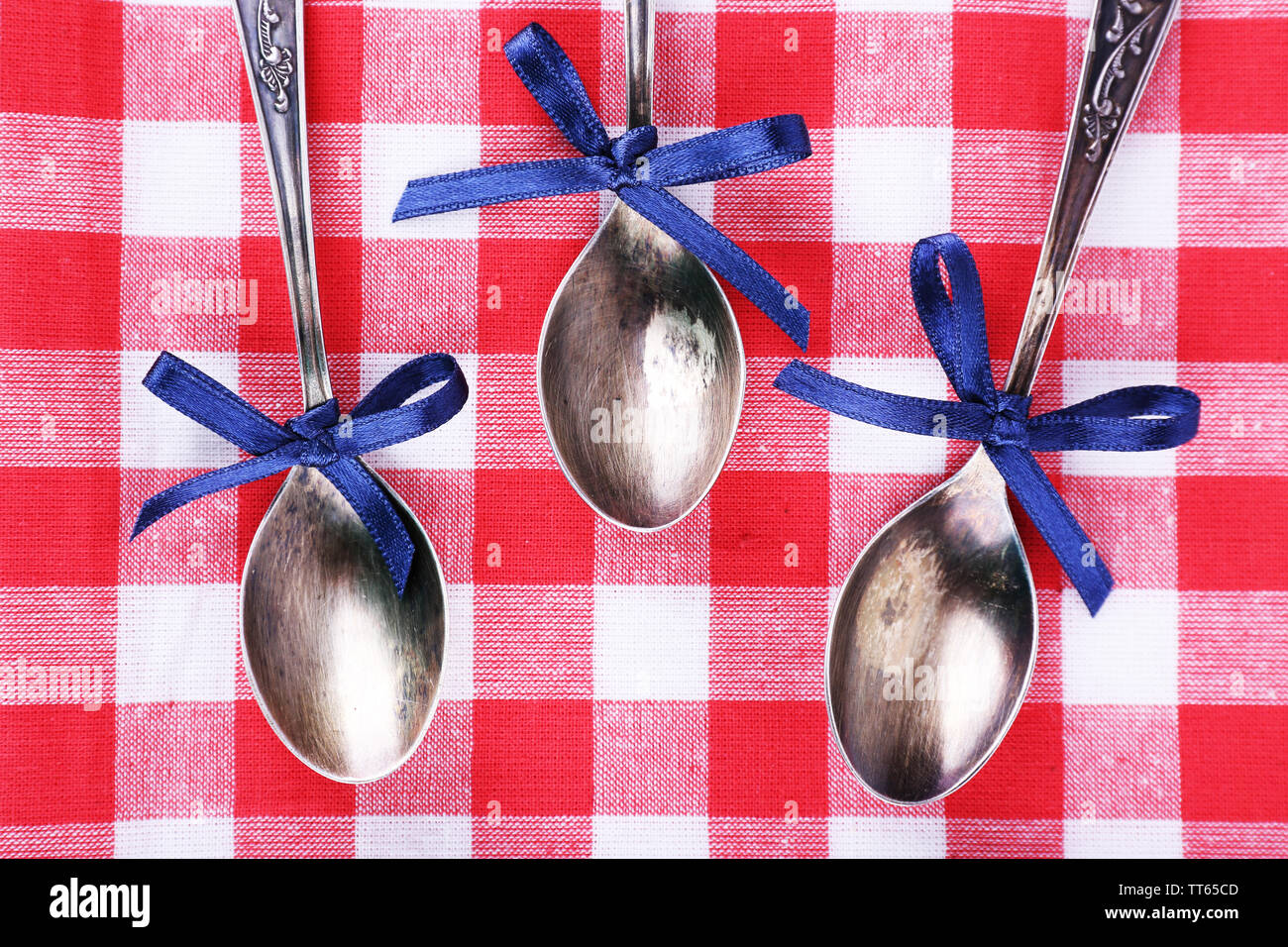 Metal spoons on checkered fabric background Stock Photo - Alamy