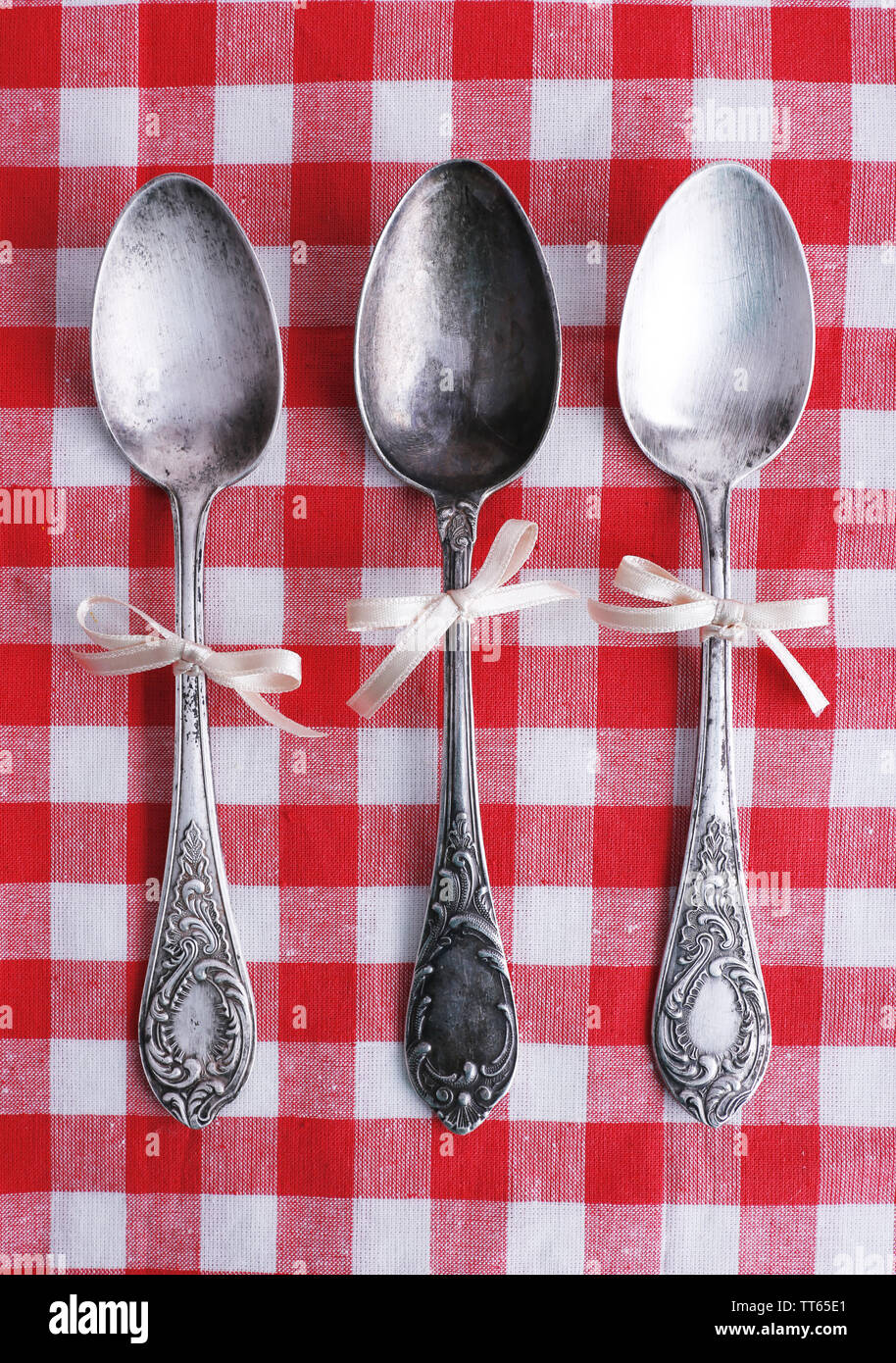 Metal spoons on checkered fabric background Stock Photo - Alamy