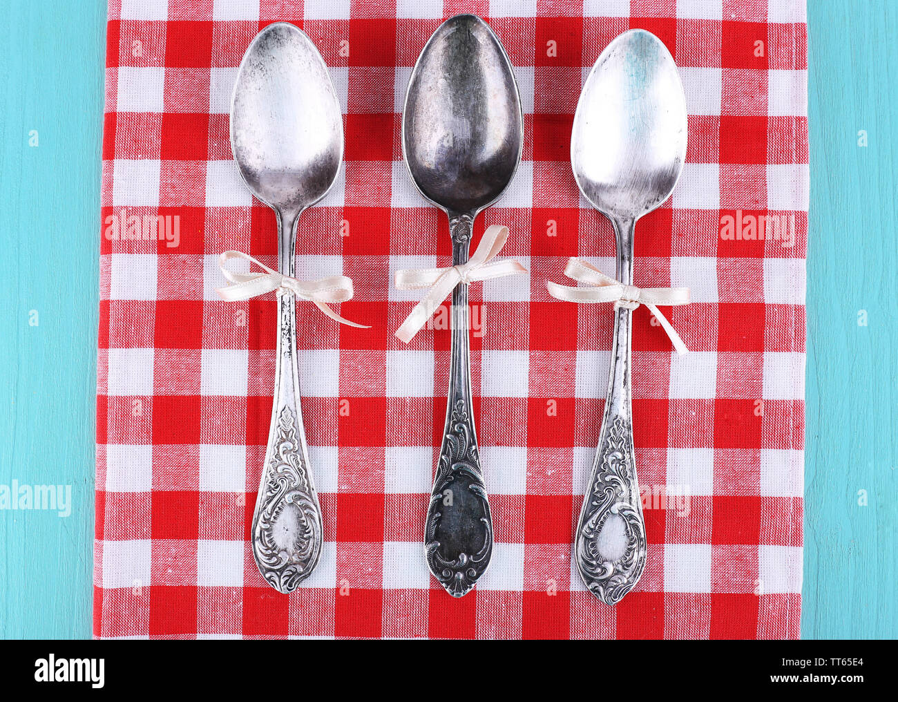 Metal spoons on checkered napkin on light blue background Stock Photo ...