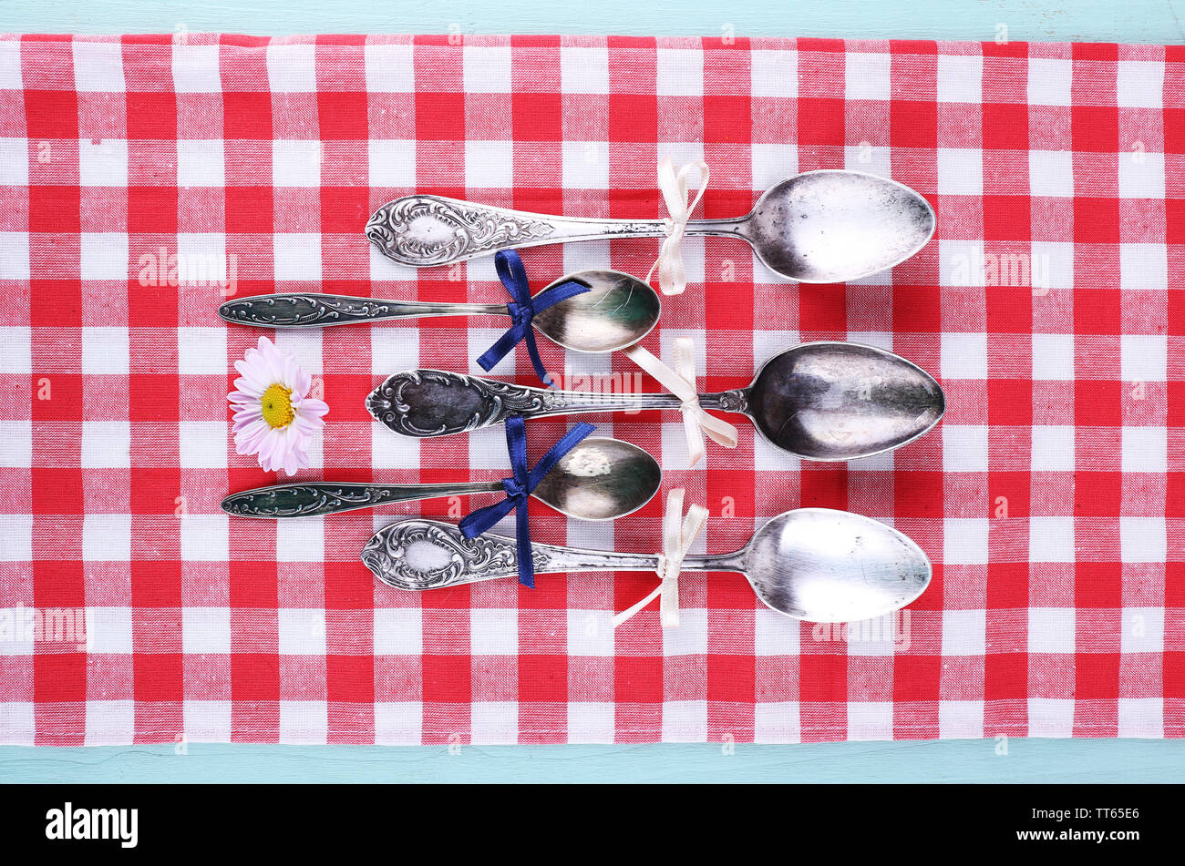 Metal spoons on checkered napkin on light blue background Stock Photo ...