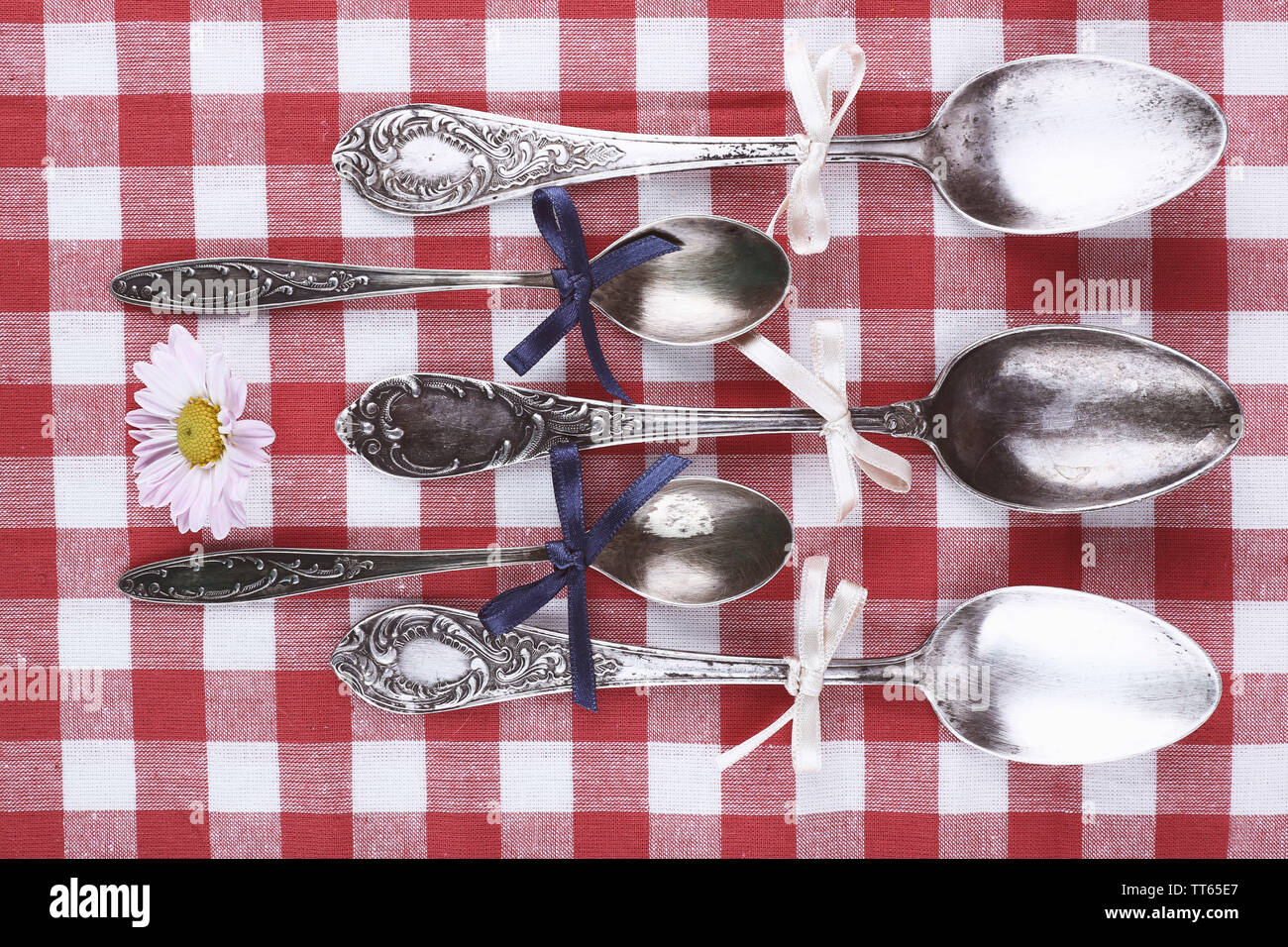 Metal spoons on checkered fabric background Stock Photo - Alamy