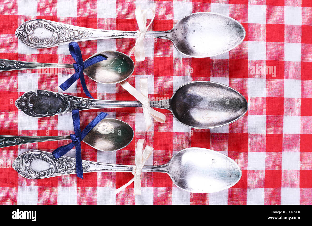 Metal spoons on checkered fabric background Stock Photo - Alamy