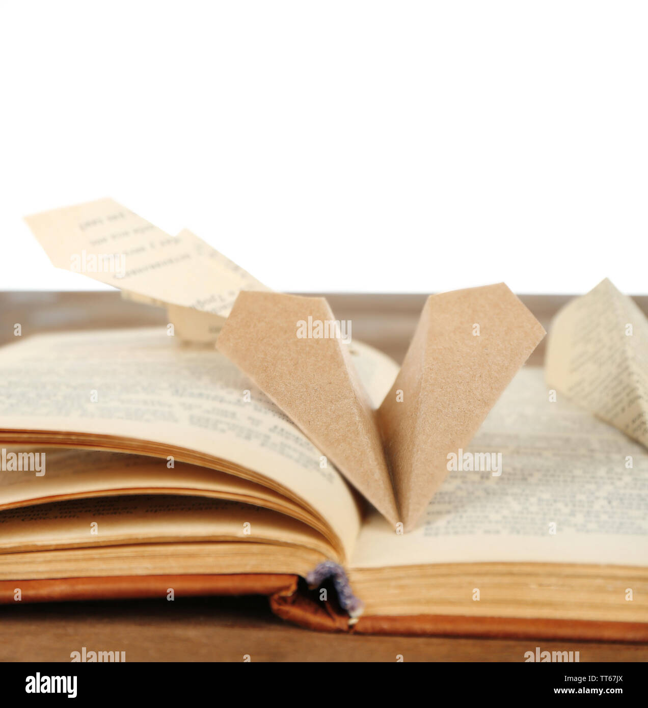 Origami airplanes on old book, on wooden table, on white background ...