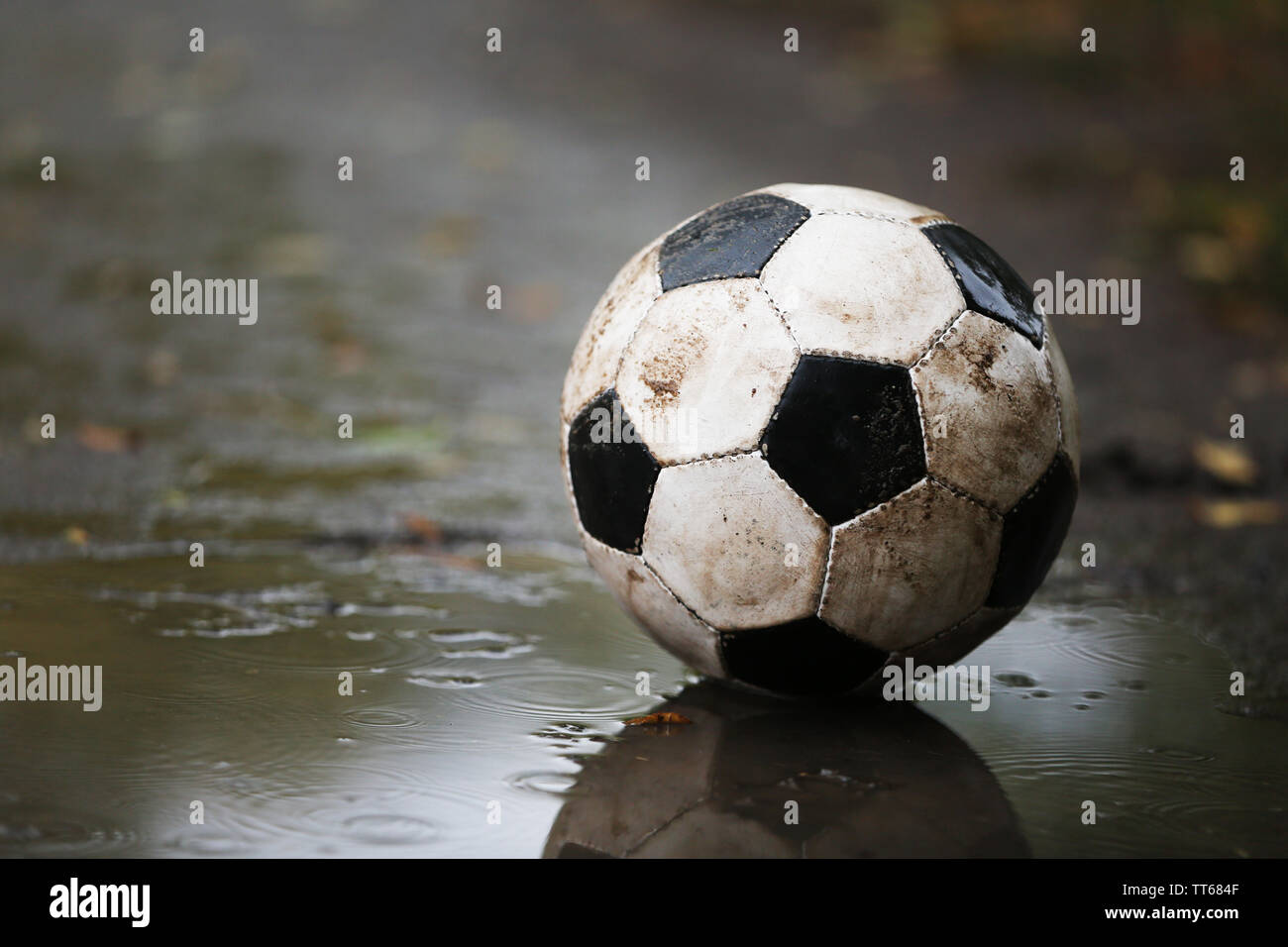 Soccer ball on ground in rainy day, outdoors Stock Photo - Alamy