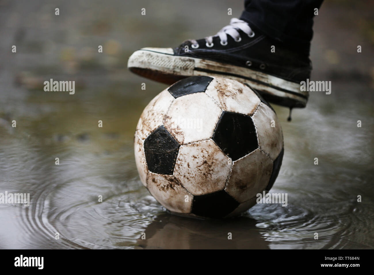 Soccer ball on ground in rainy day, outdoors Stock Photo - Alamy