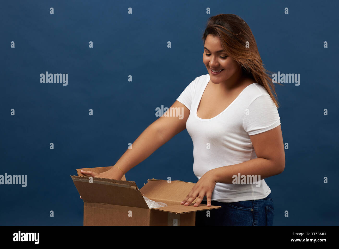 Young woman unboxing package isolated on blue studio background Stock ...