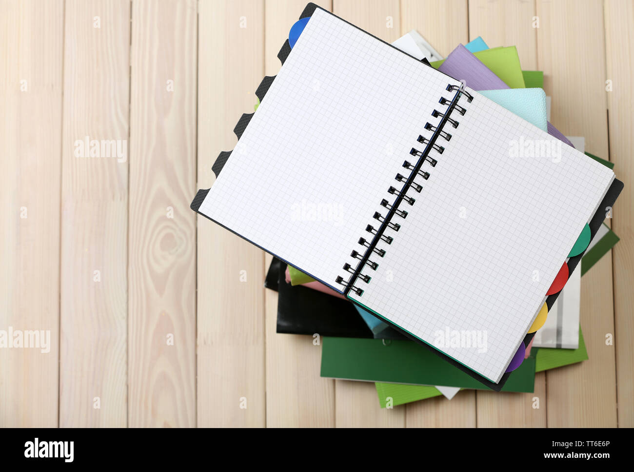 Notebook on top of pile of books and magazines on wooden background ...
