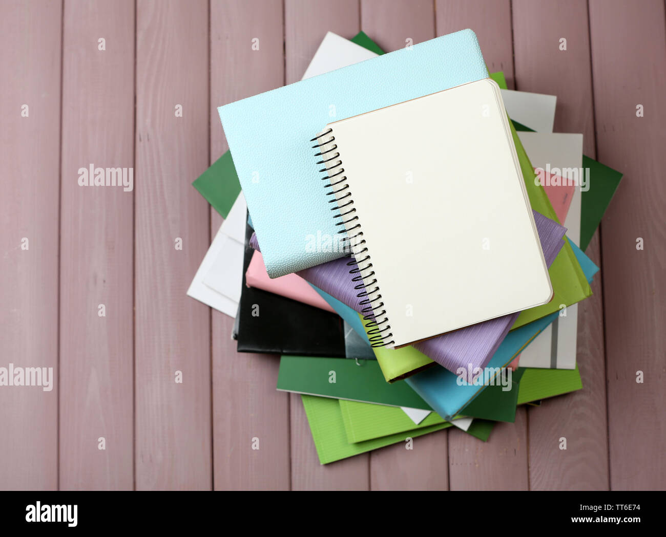 Notebook on top of pile of books and magazines on wooden background ...