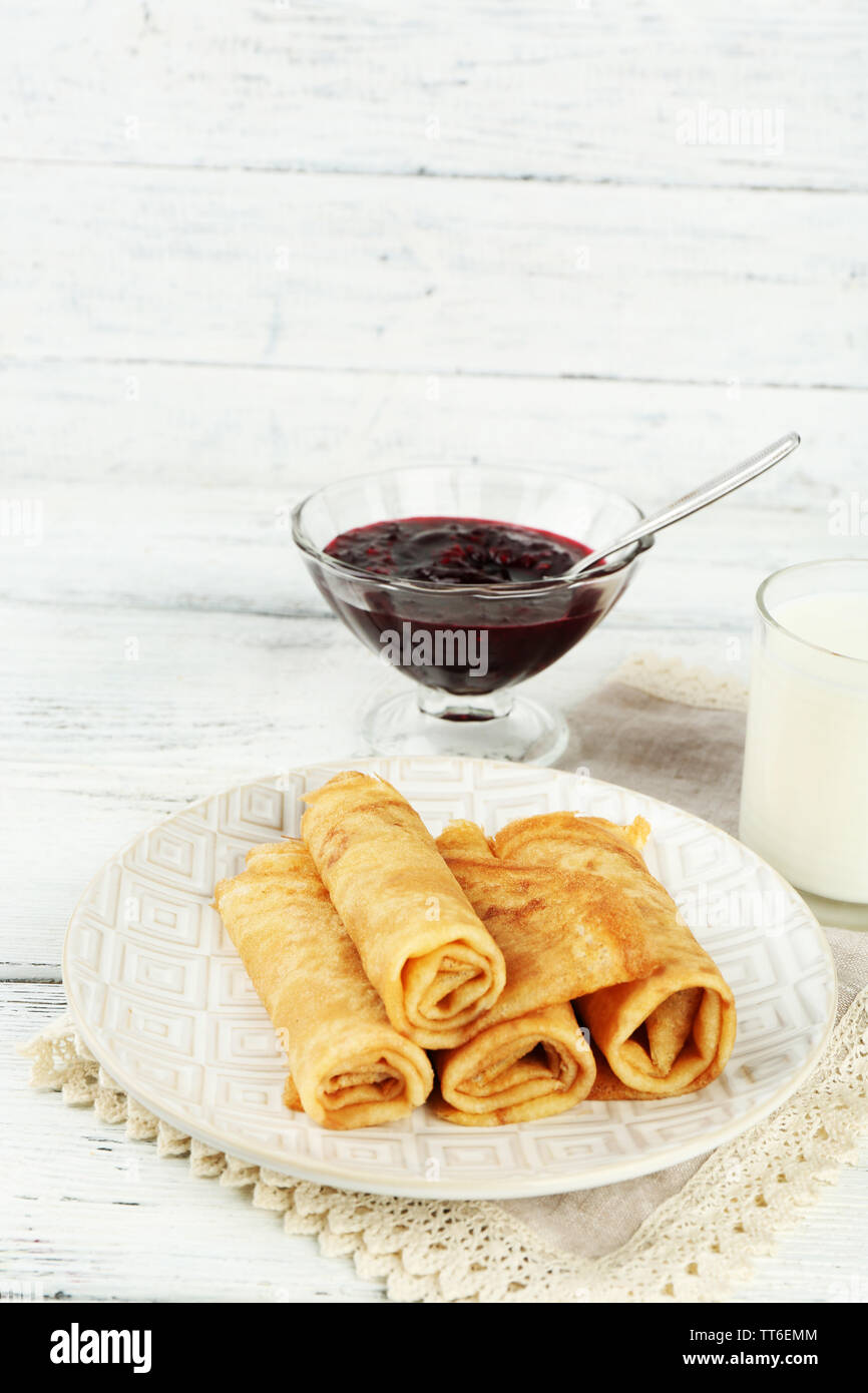 Plate of delicious pancakes and berry jam in glass bowl, glass of milk ...