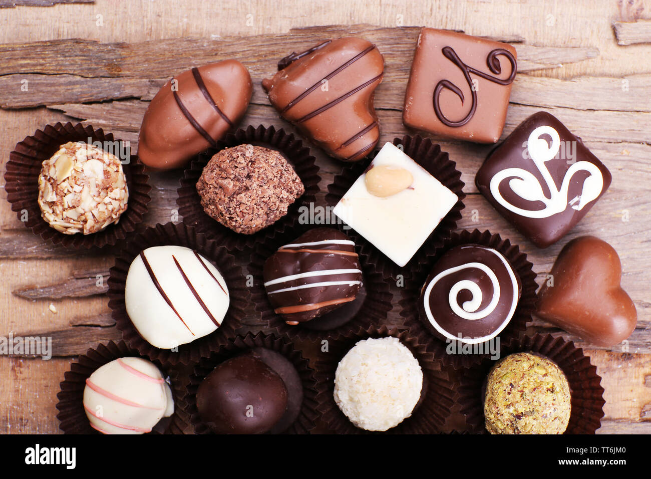 Many chocolates on wooden textured background Stock Photo - Alamy