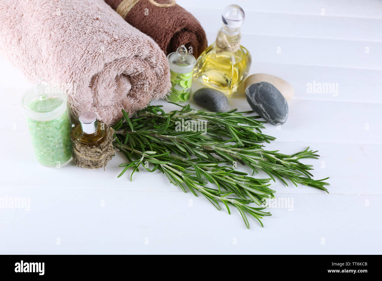 Branches of rosemary, towels and bottle with massage oil on color ...