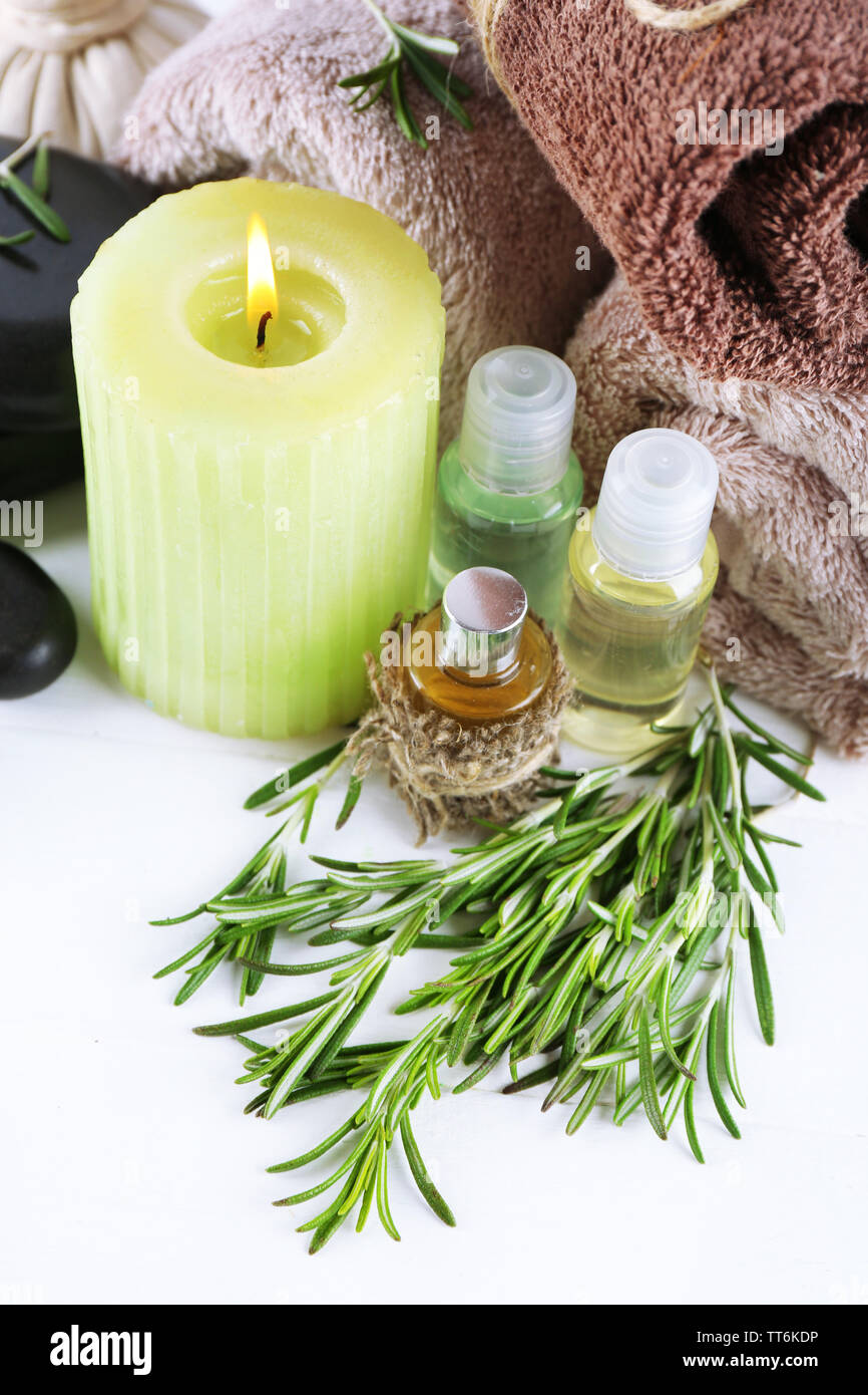 Branches of rosemary and sea salt, towels, candle and bottle with ...