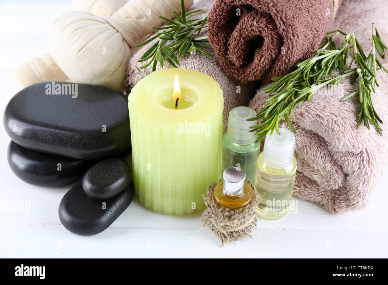 Branches of rosemary and sea salt, towels, candle and bottle with ...