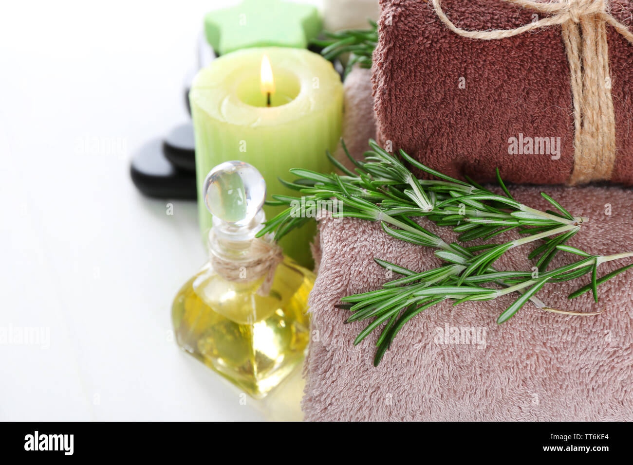 Branches of rosemary and sea salt, towels, candle and bottle with ...