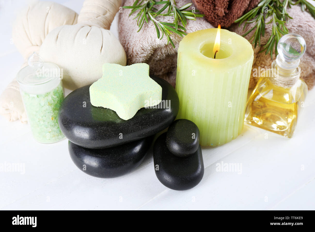 Branches of rosemary and sea salt, towels, candle and bottle with ...