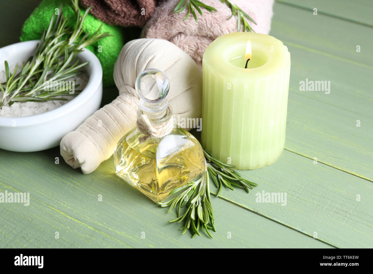 Branches of rosemary and sea salt in bowl, towels, candle and bottle ...