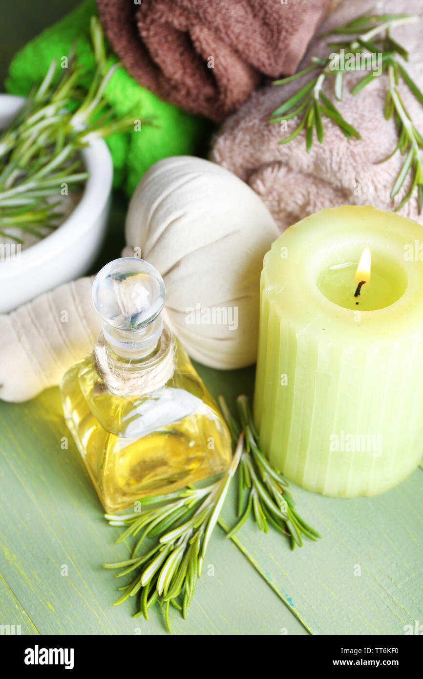 Branches of rosemary and sea salt in bowl, towels, candle and bottle ...