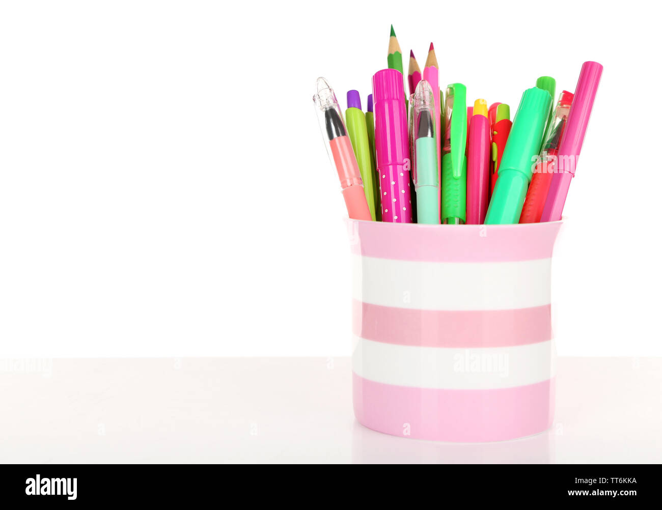 Colorful pens,pencils and markers in striped plastic cup isolated on ...