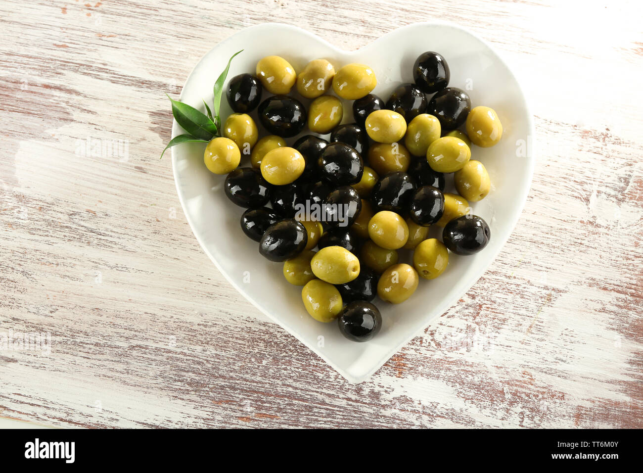 Plate in the form of heart with black and green olives on painted ...