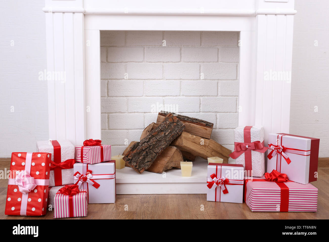 Present boxes near the fireplace with firewood on wooden floor and whit ...