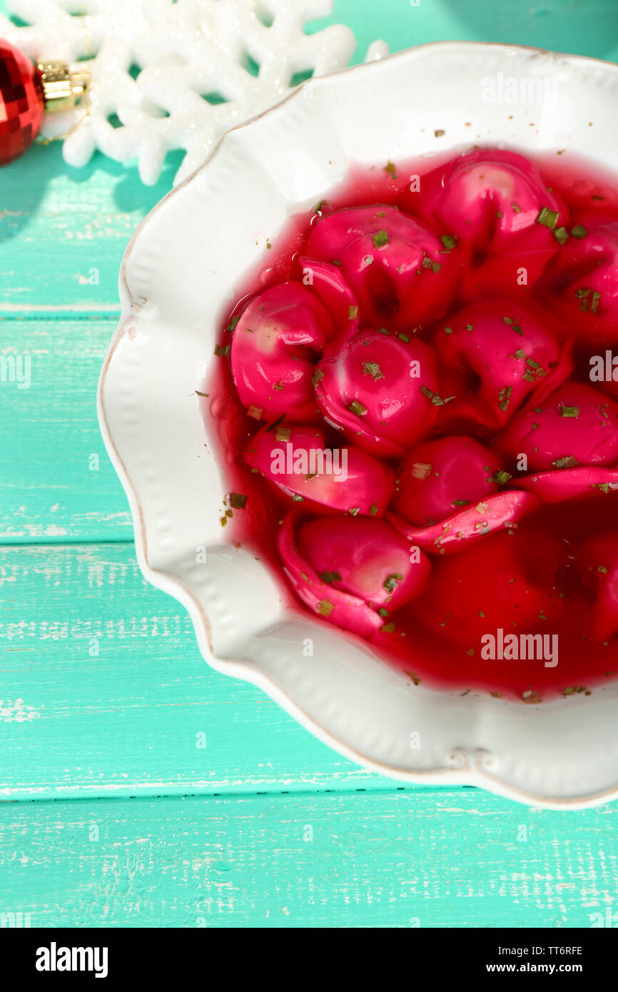 Traditional polish clear red borscht with dumplings on color wooden ...