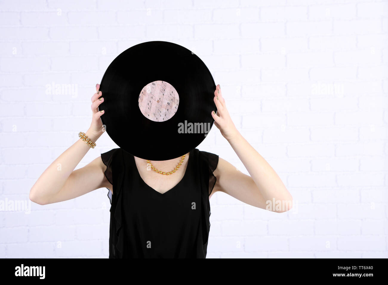 Young woman holding retro record in front of face, on shiny background ...