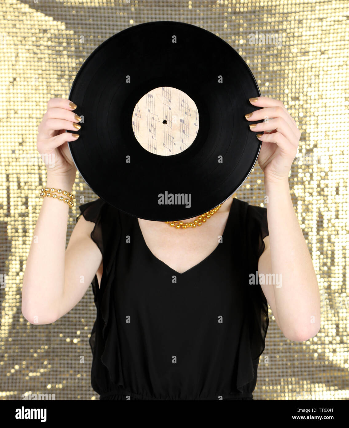 Young woman holding retro record in front of face, on shiny background ...
