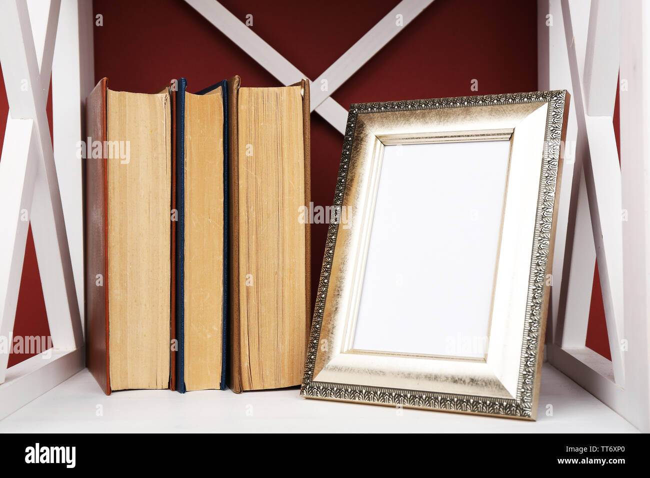 Photo frame with books on shelf, on color wall background Stock Photo ...