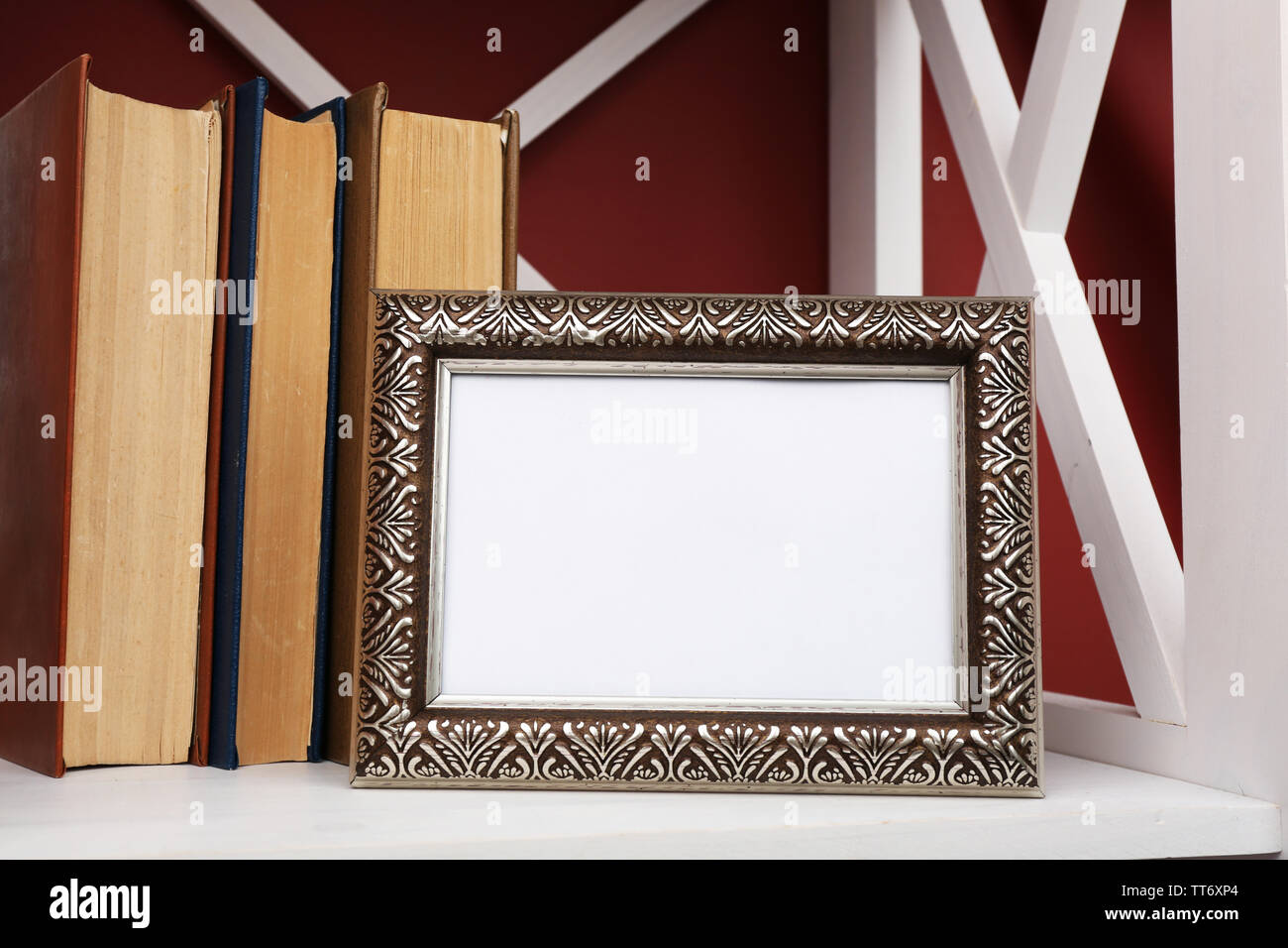Photo frame with books on shelf, on color wall background Stock Photo ...
