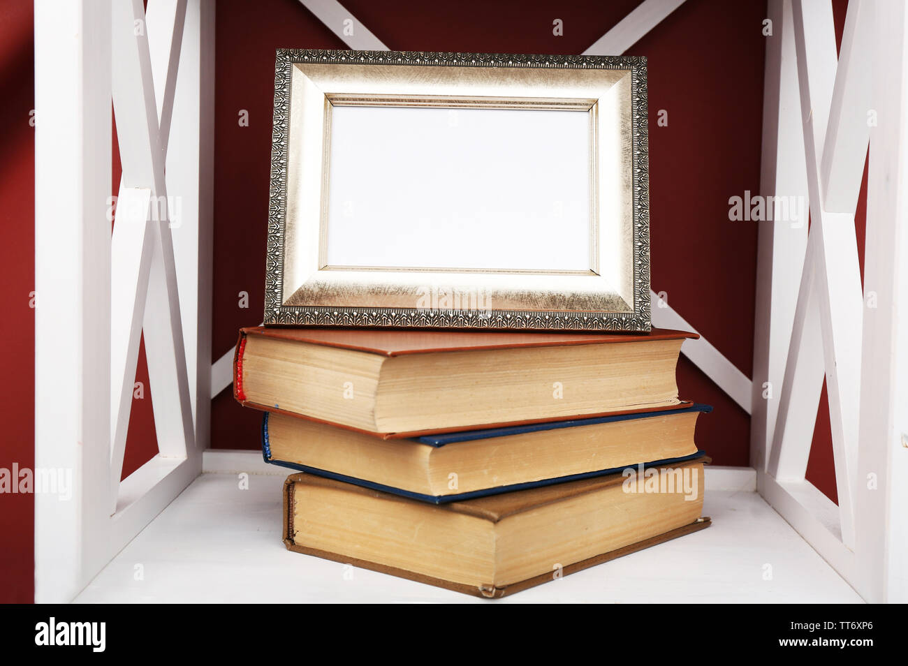 Photo frame with books on shelf, on color wall background Stock Photo ...