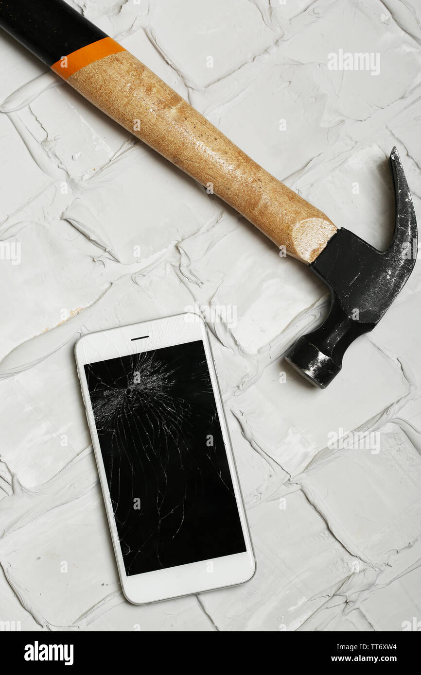 Broken iPhone with hammer on brick background Stock Photo - Alamy