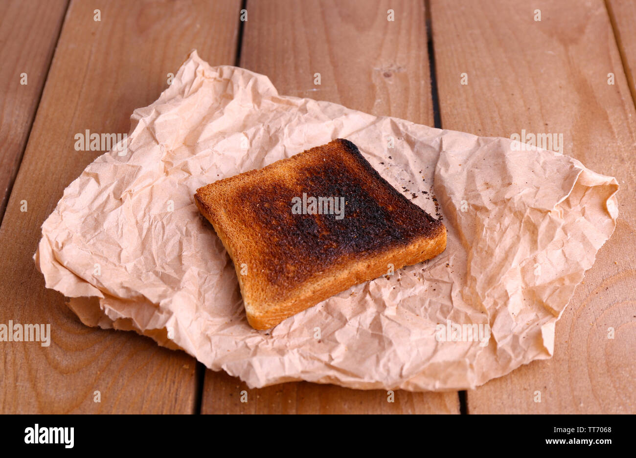 Burnt toasted bread on piece of paper and wooden table background Stock ...
